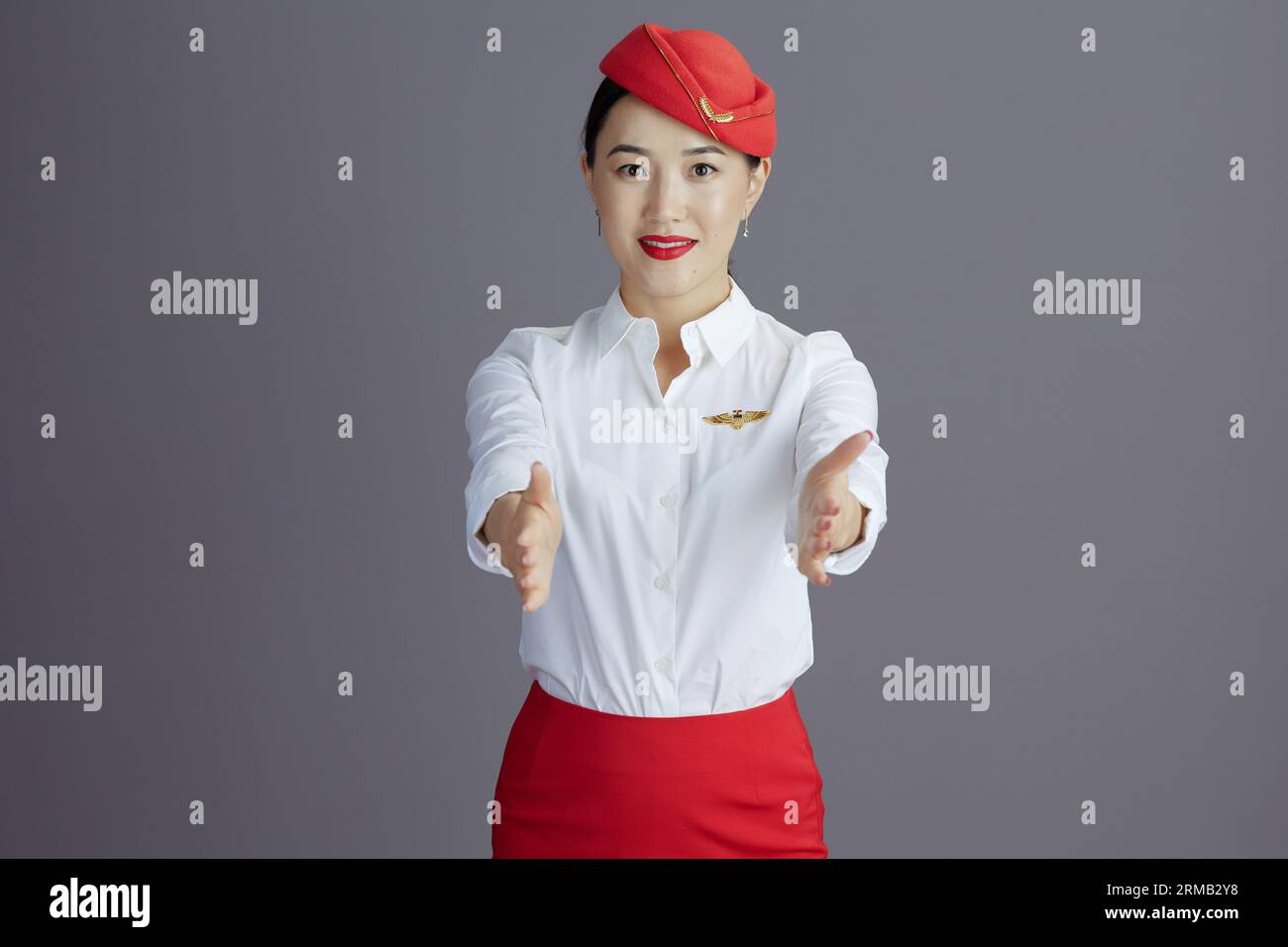 stylish asian female stewardess in red skirt and hat uniform showing ...