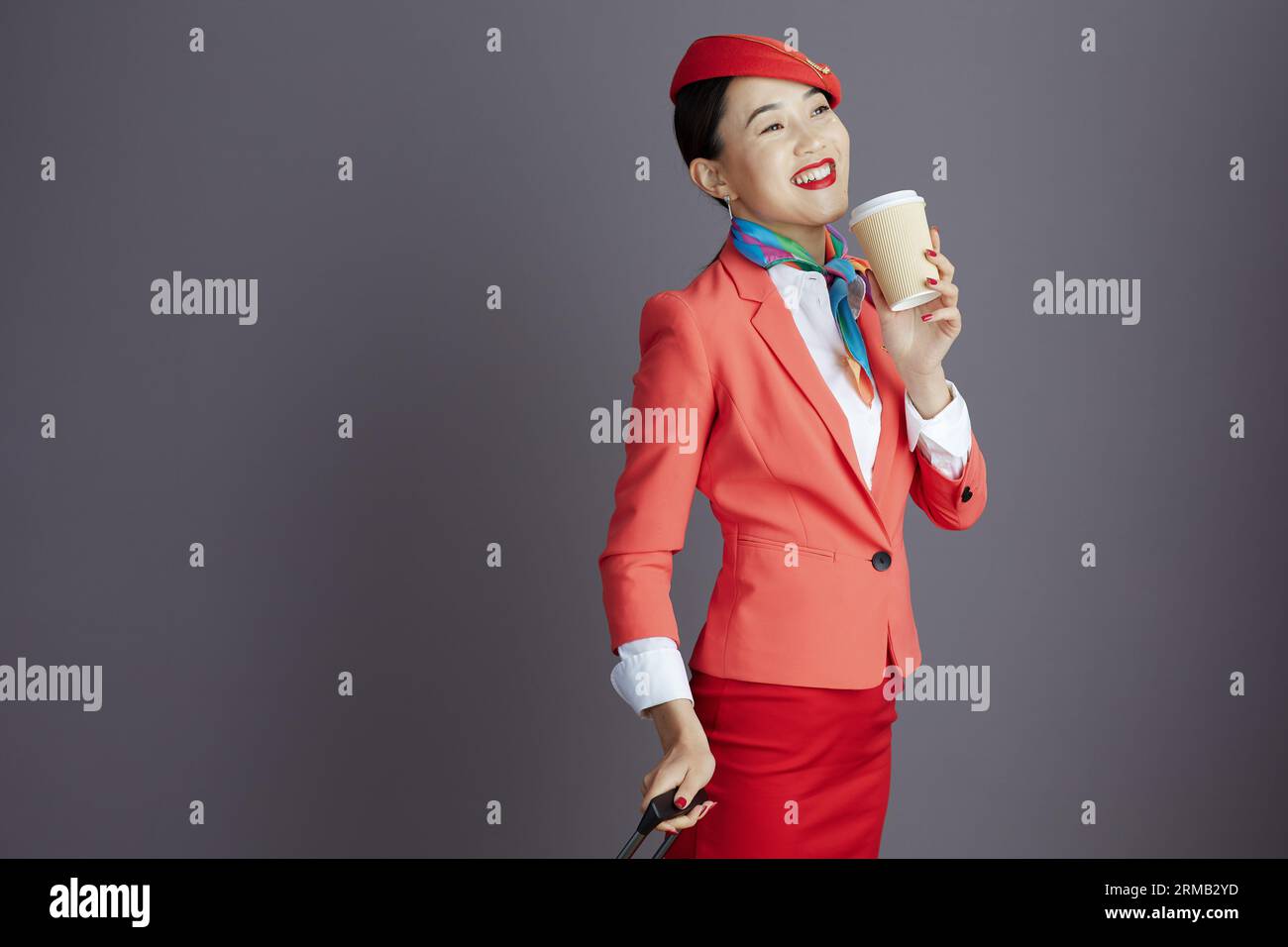 smiling elegant air hostess asian woman in red skirt, jacket and hat ...