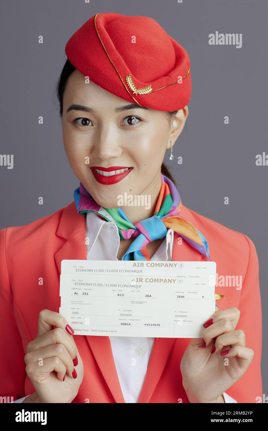 happy modern asian female air hostess in red skirt, jacket and hat ...
