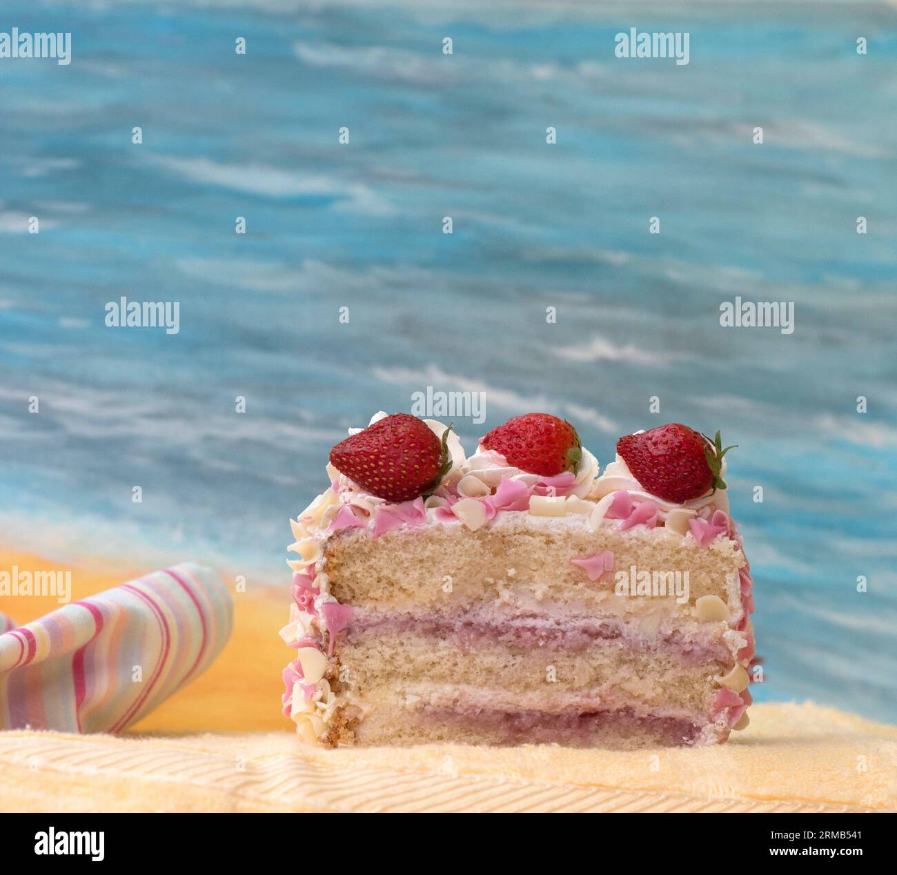 A slice of fancy pink chocolate celebration Cake on beach at seaside ...