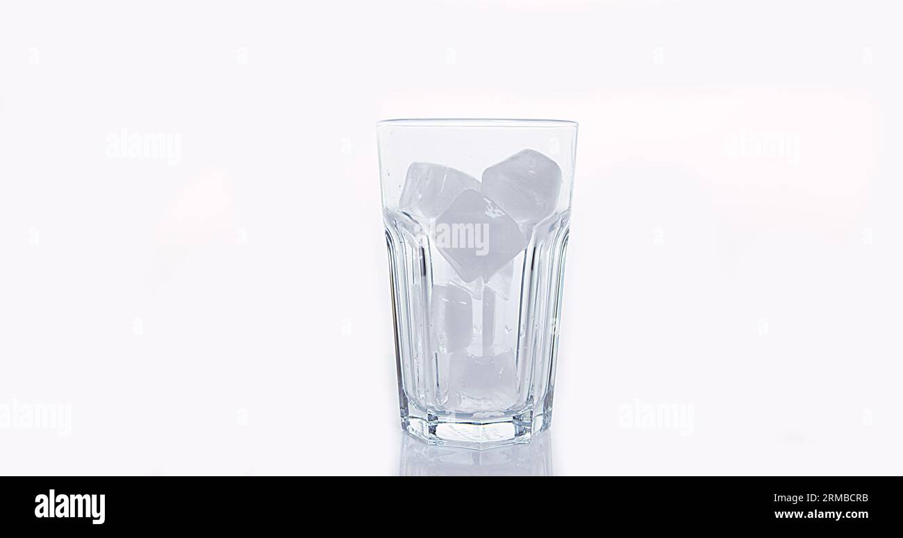 Ice Cubes Falling into Glass against White Background Stock Photo - Alamy