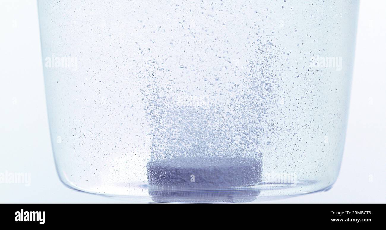 Tablets Falling and Dissolving into a Glass of Water against White ...