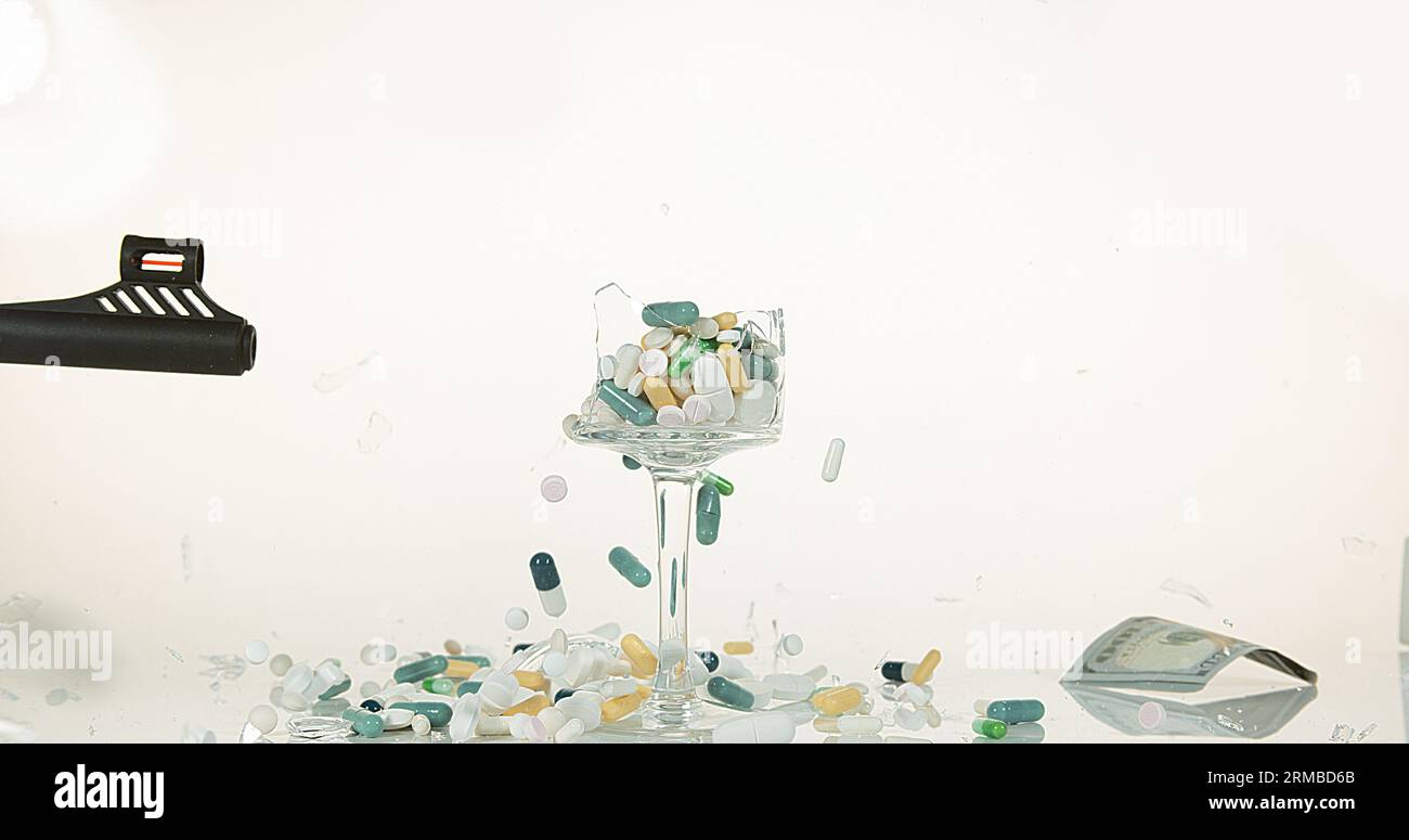 Glass filled with Capsules and Dollars Exploding against White ...