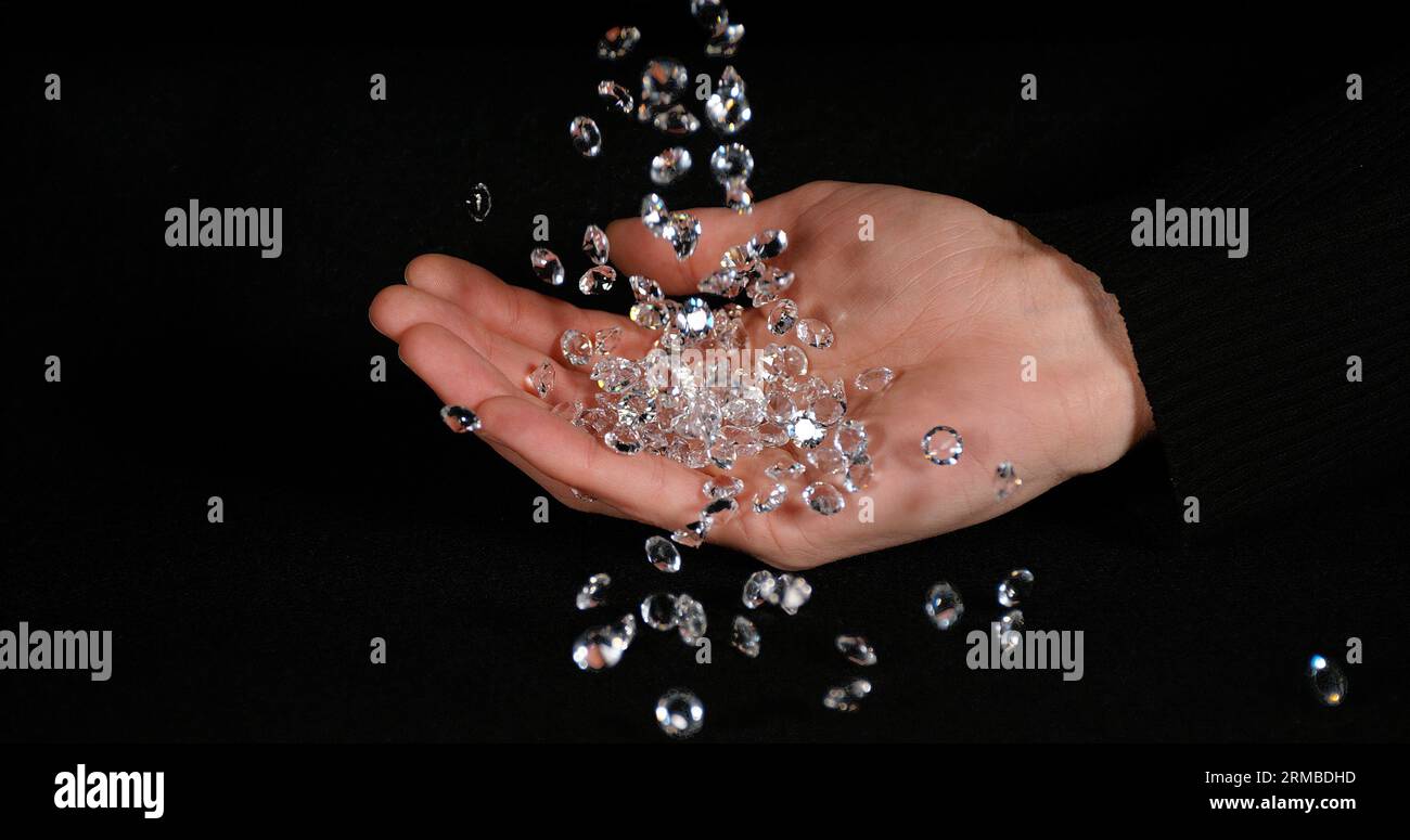 Diamonds falling into Hand against Black Background Stock Photo - Alamy