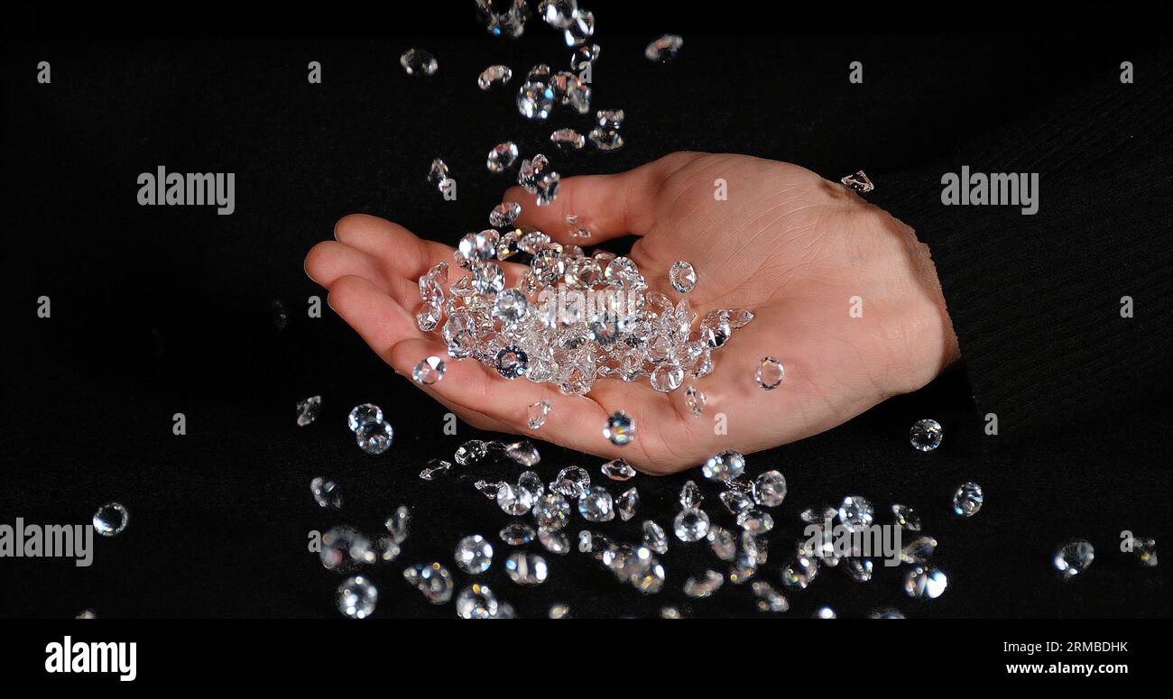 Diamonds falling into Hand against Black Background Stock Photo - Alamy