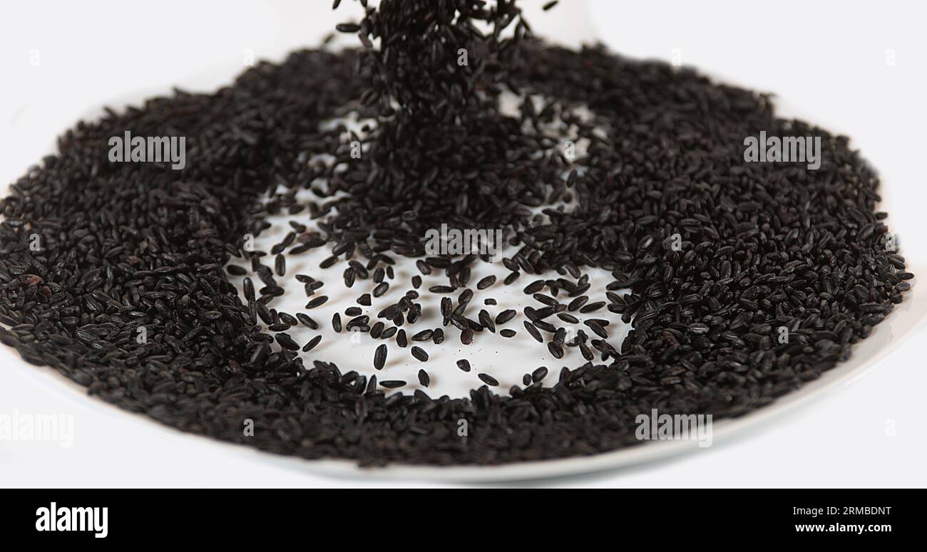 Black Rice falling into Plate Stock Photo - Alamy