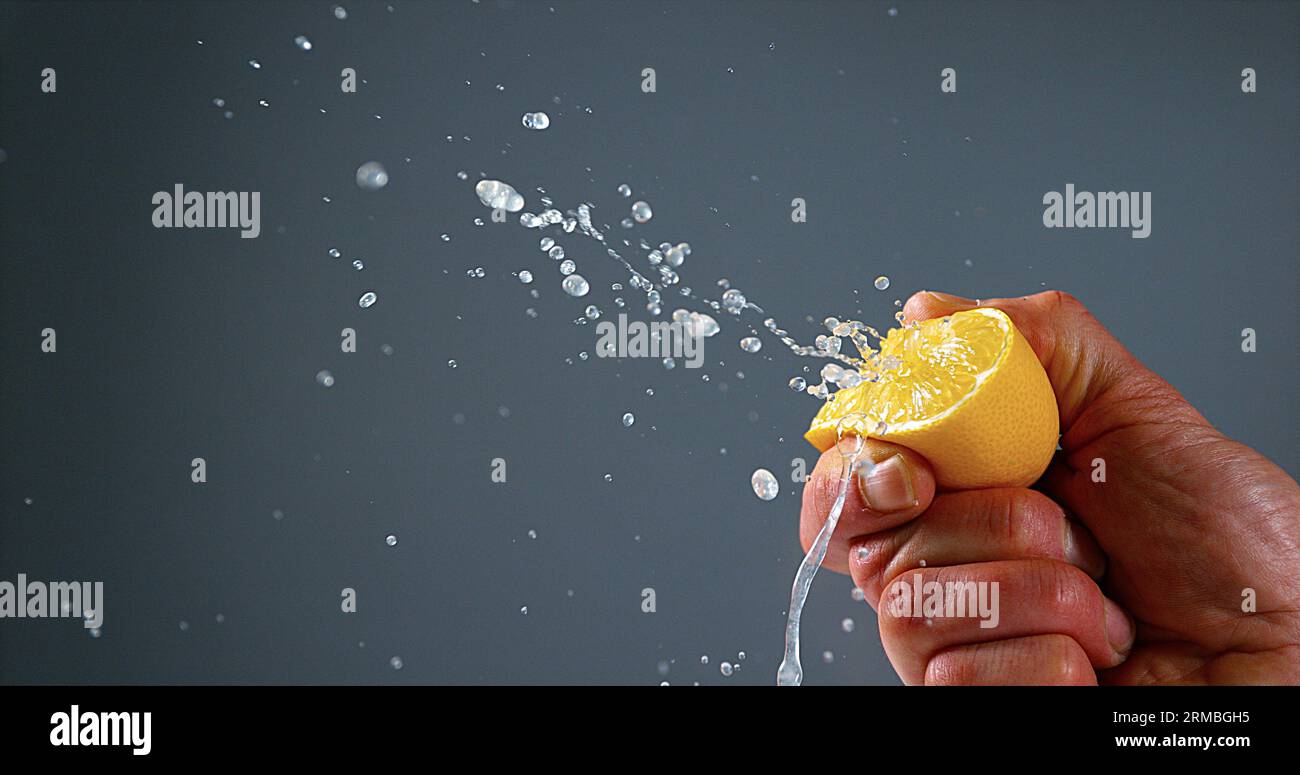 Hand of Man Squeezing Lemon, citrus limonum against Black Background ...