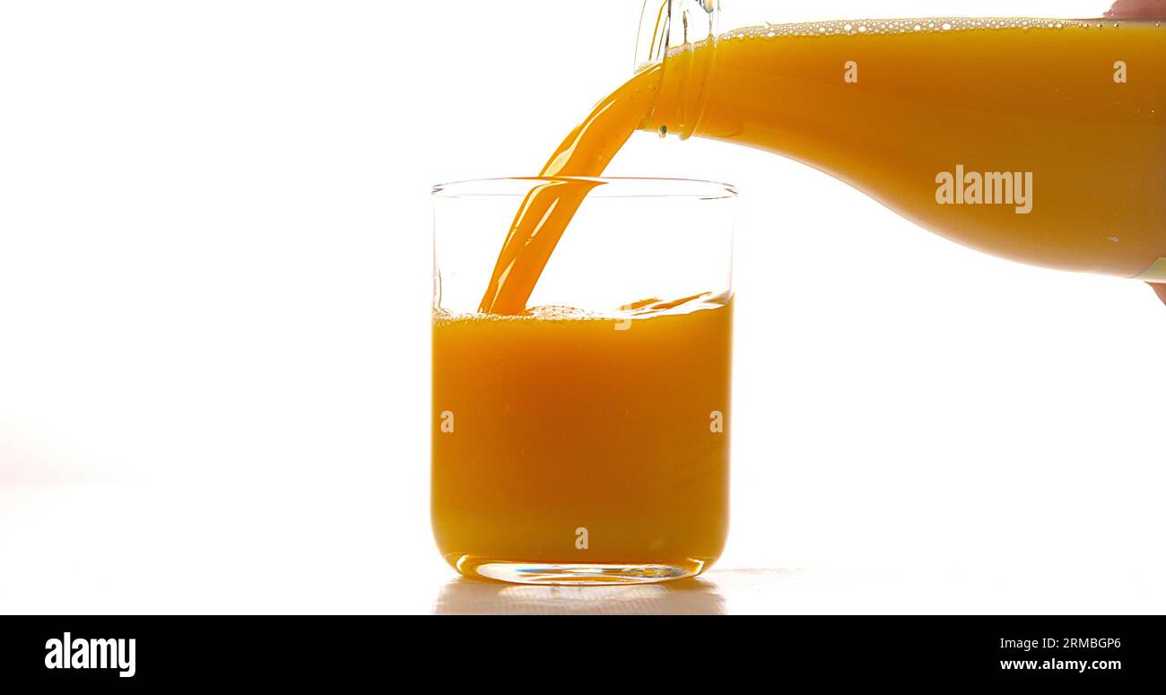Orange Juice being poured into Glass against White Background Stock ...