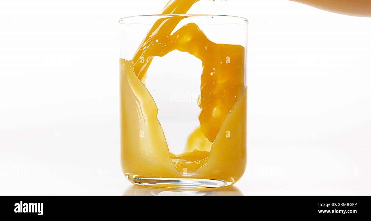 Orange Juice being poured into Glass against White Background Stock ...
