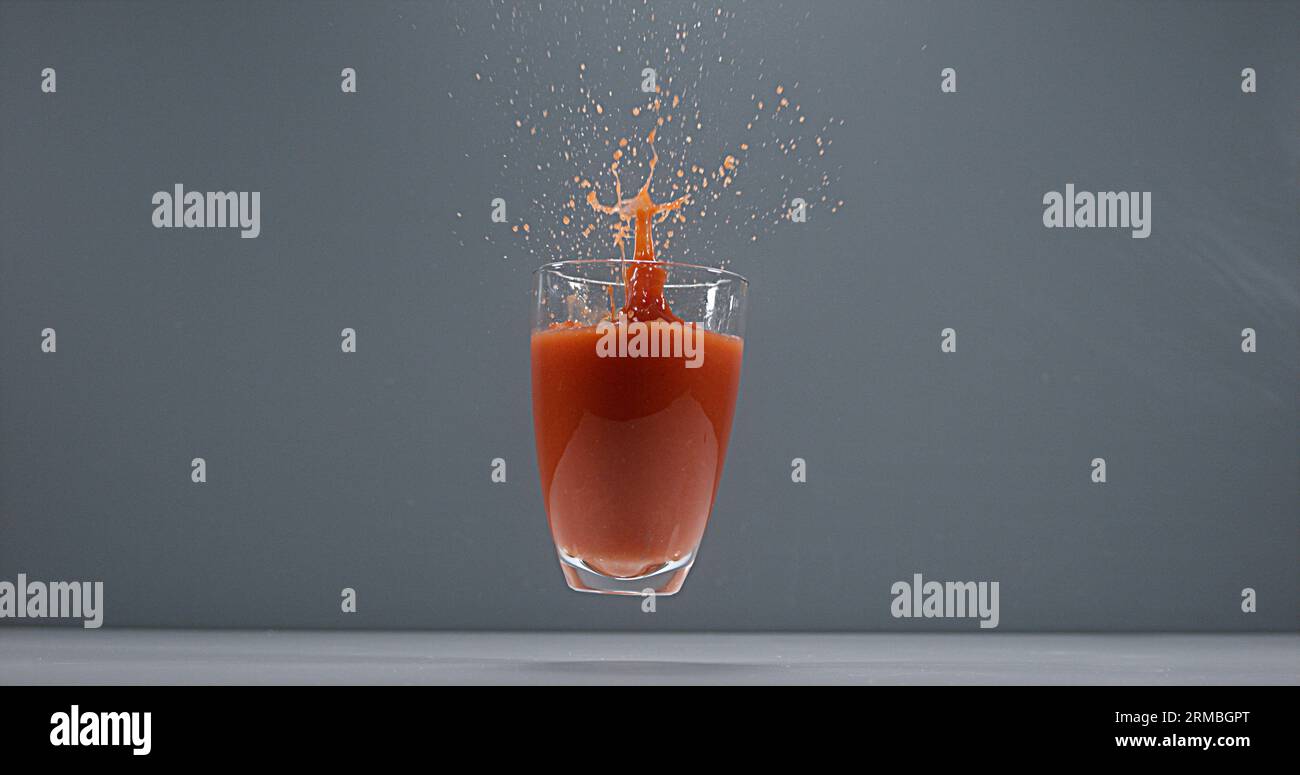 Glass of Tomatoe's Juice falling Stock Photo - Alamy