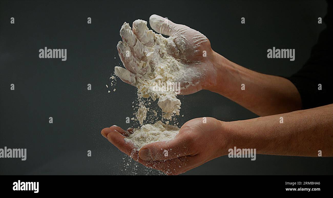 Hands of Man with Flour against black background Stock Photo - Alamy