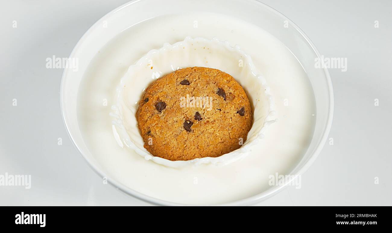 Cookie falling into a Milk Bowl against White background Stock Photo ...