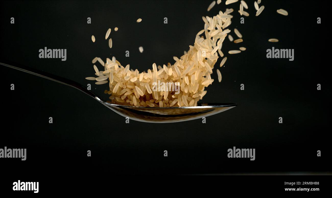 Rice falling in a Spoon against Black Background Stock Photo - Alamy
