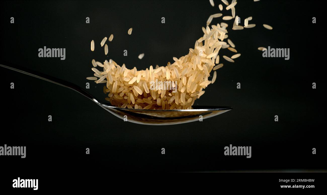 Rice falling in a Spoon against Black Background Stock Photo - Alamy