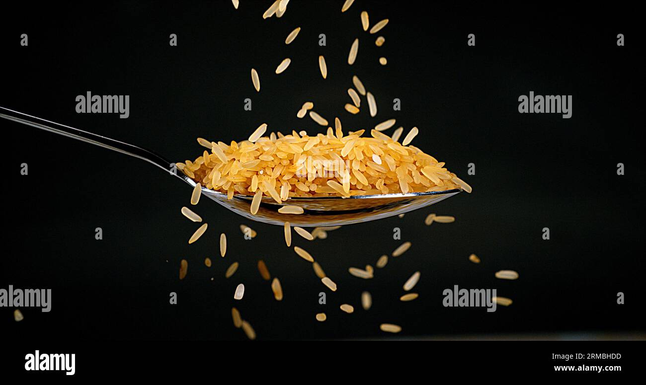 Rice falling in a Spoon against Black Background Stock Photo - Alamy