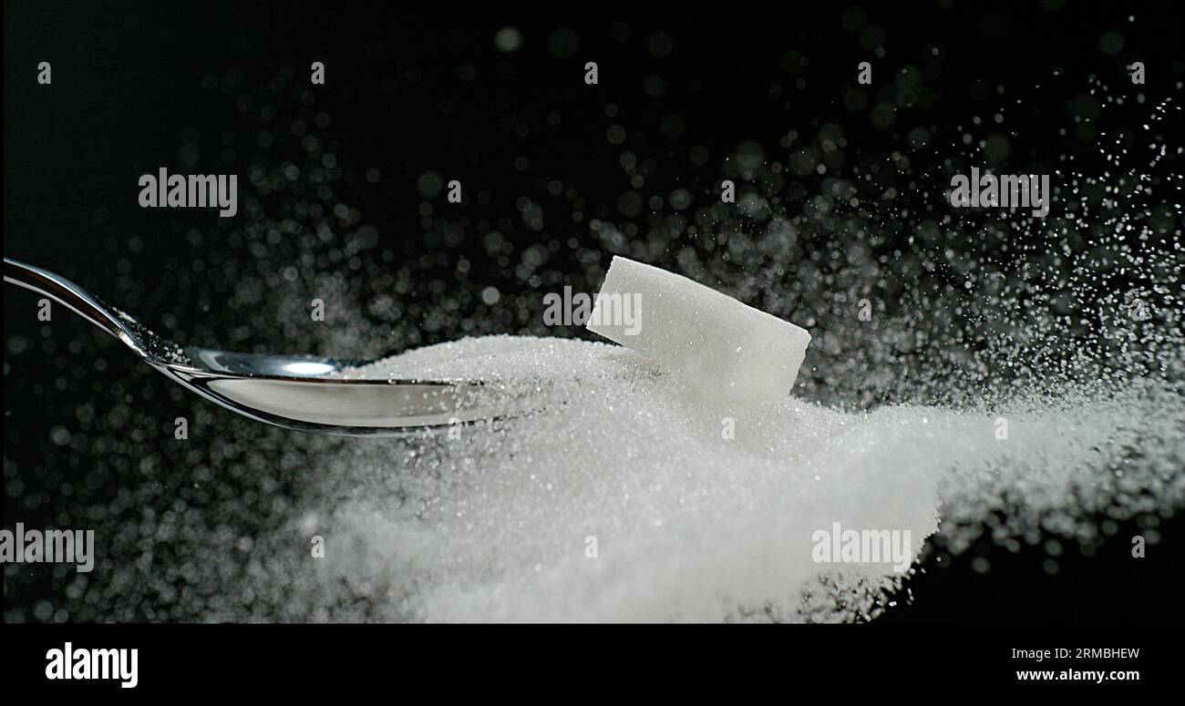 White Sugar Cube falling on Powder Sugar against Black Background Stock ...