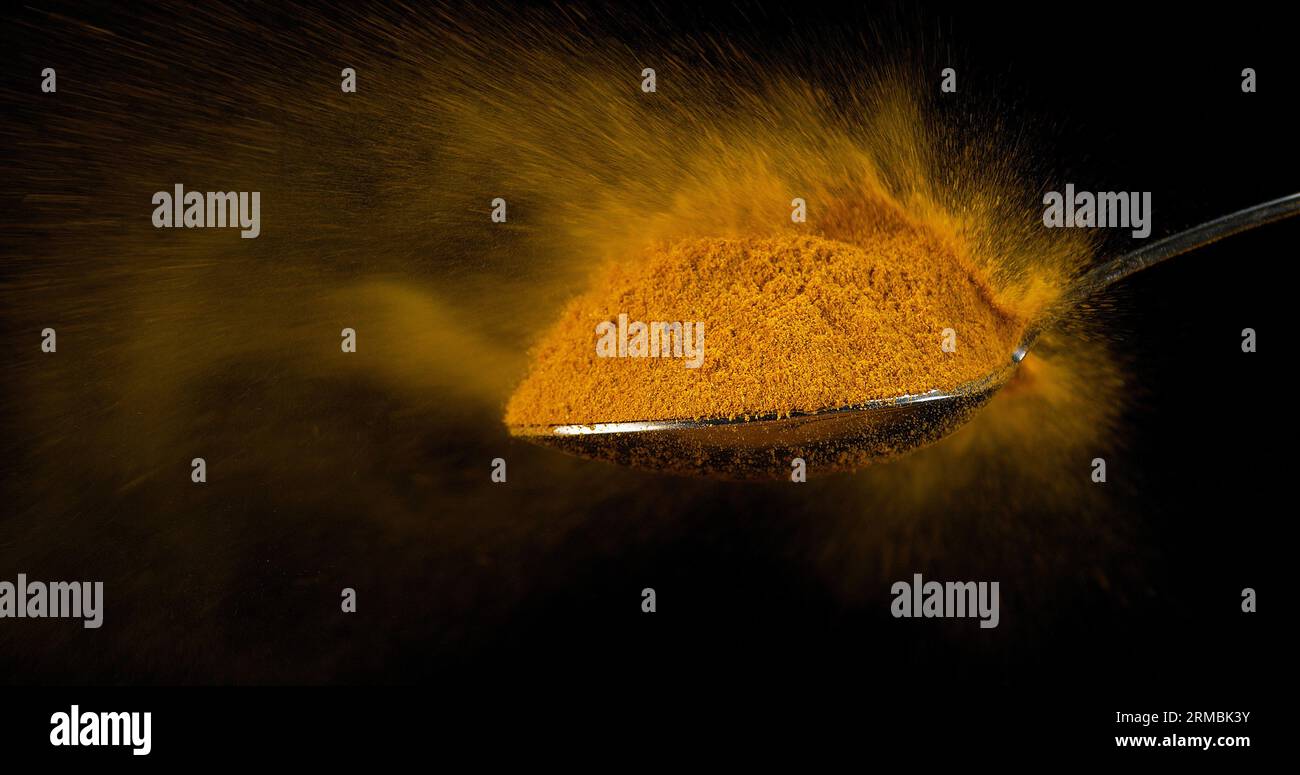 Spoon and Curry Powder falling from Spoon against Black Background ...