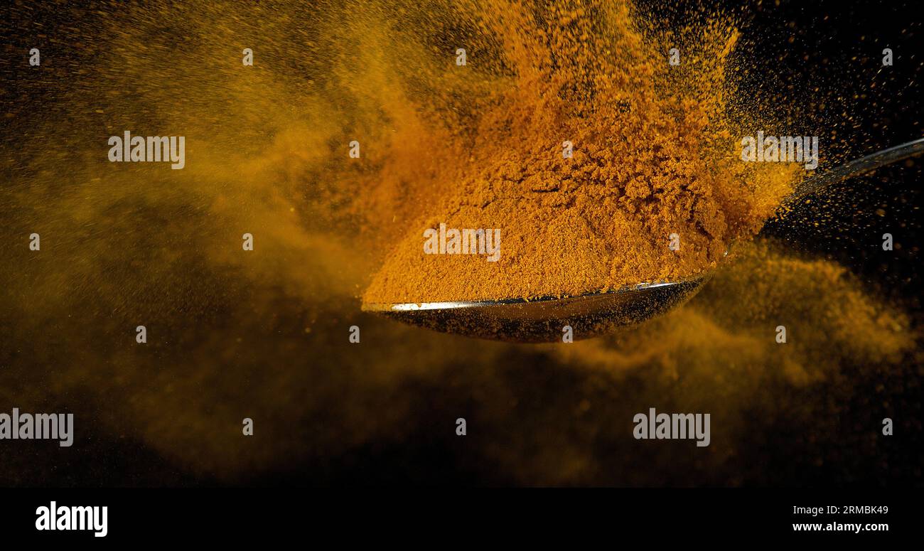 Spoon and Curry Powder falling from Spoon against Black Background ...