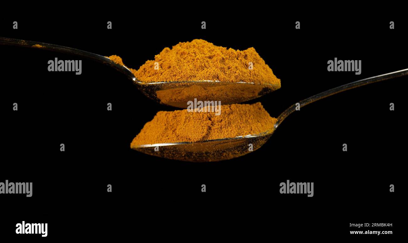 Spoon and Curry Powder falling from Spoon against Black Background ...