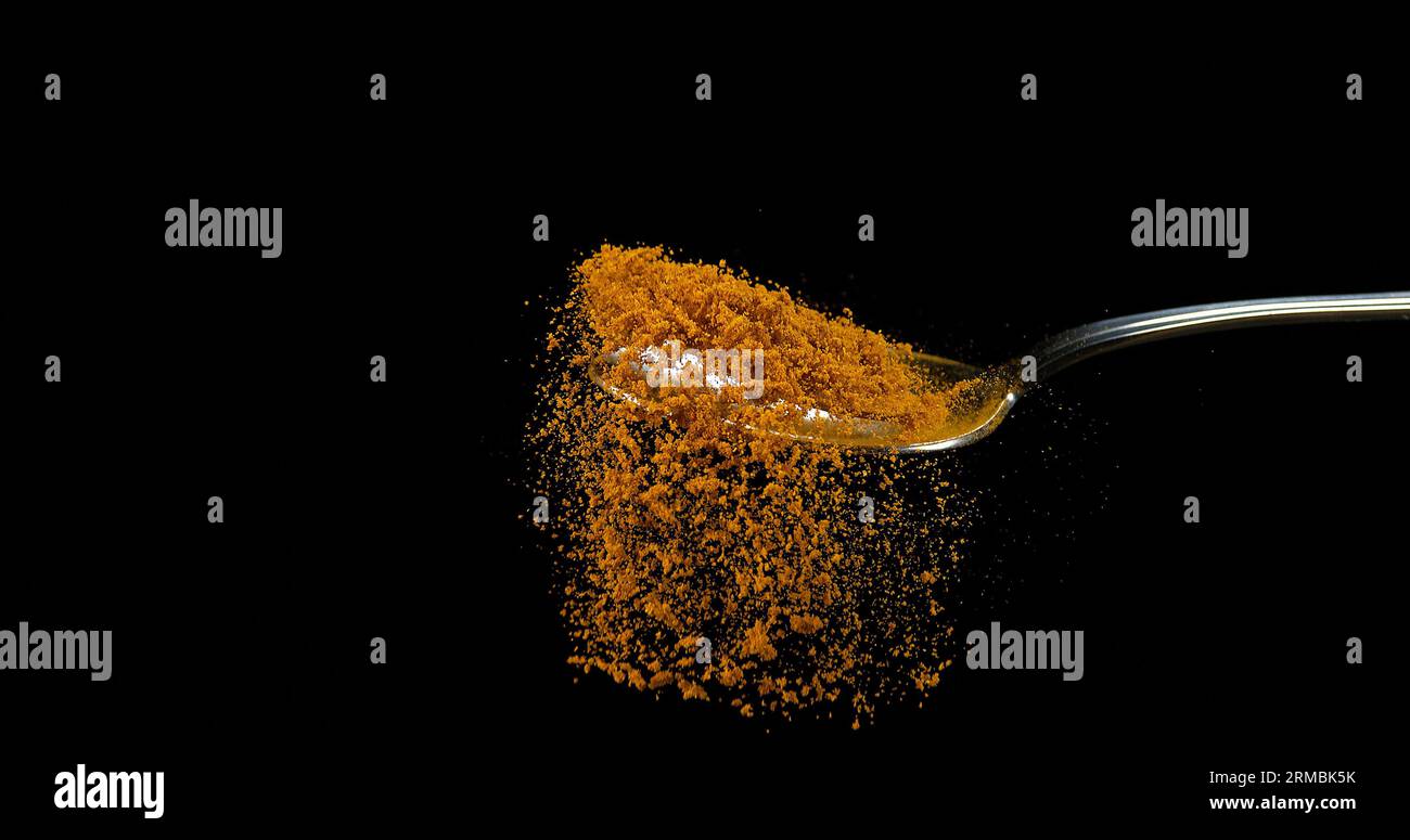 Spoon and Curry Powder falling from Spoon against Black Background ...