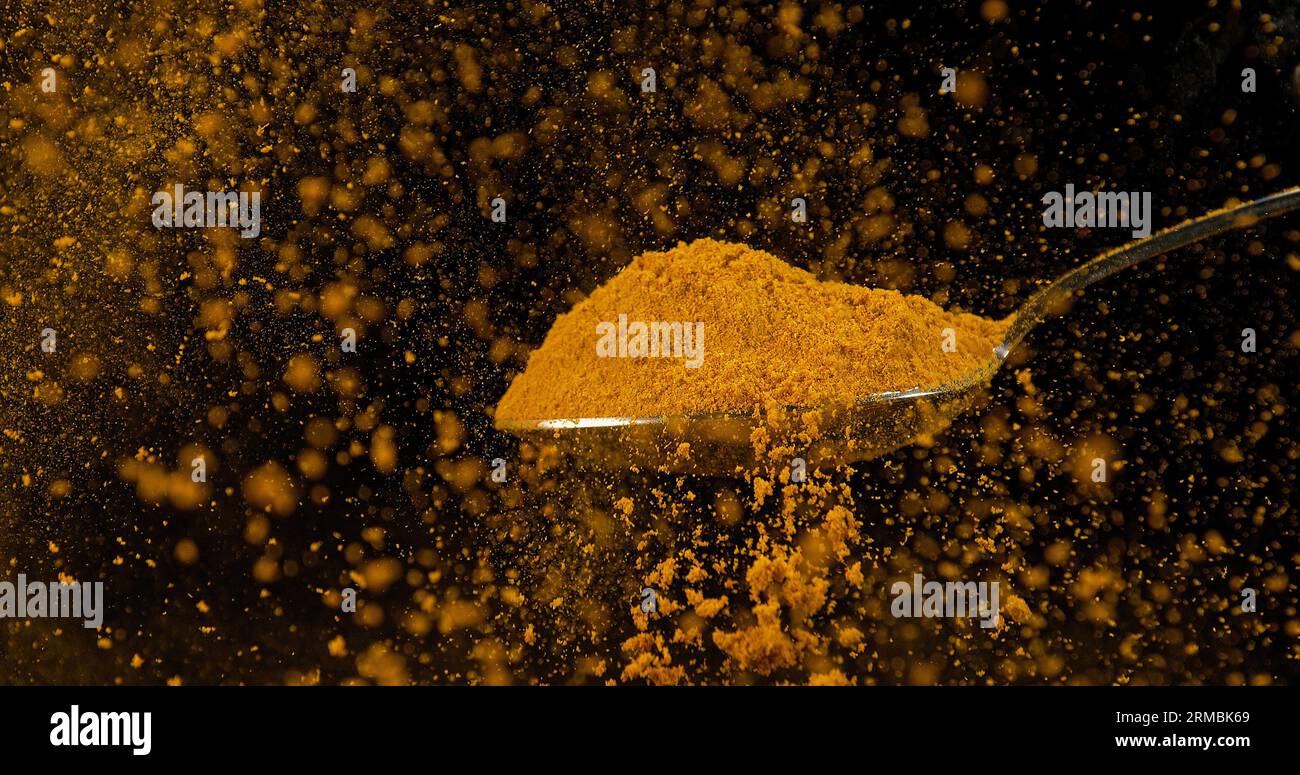 Spoon and Curry Powder falling from Spoon against Black Background ...