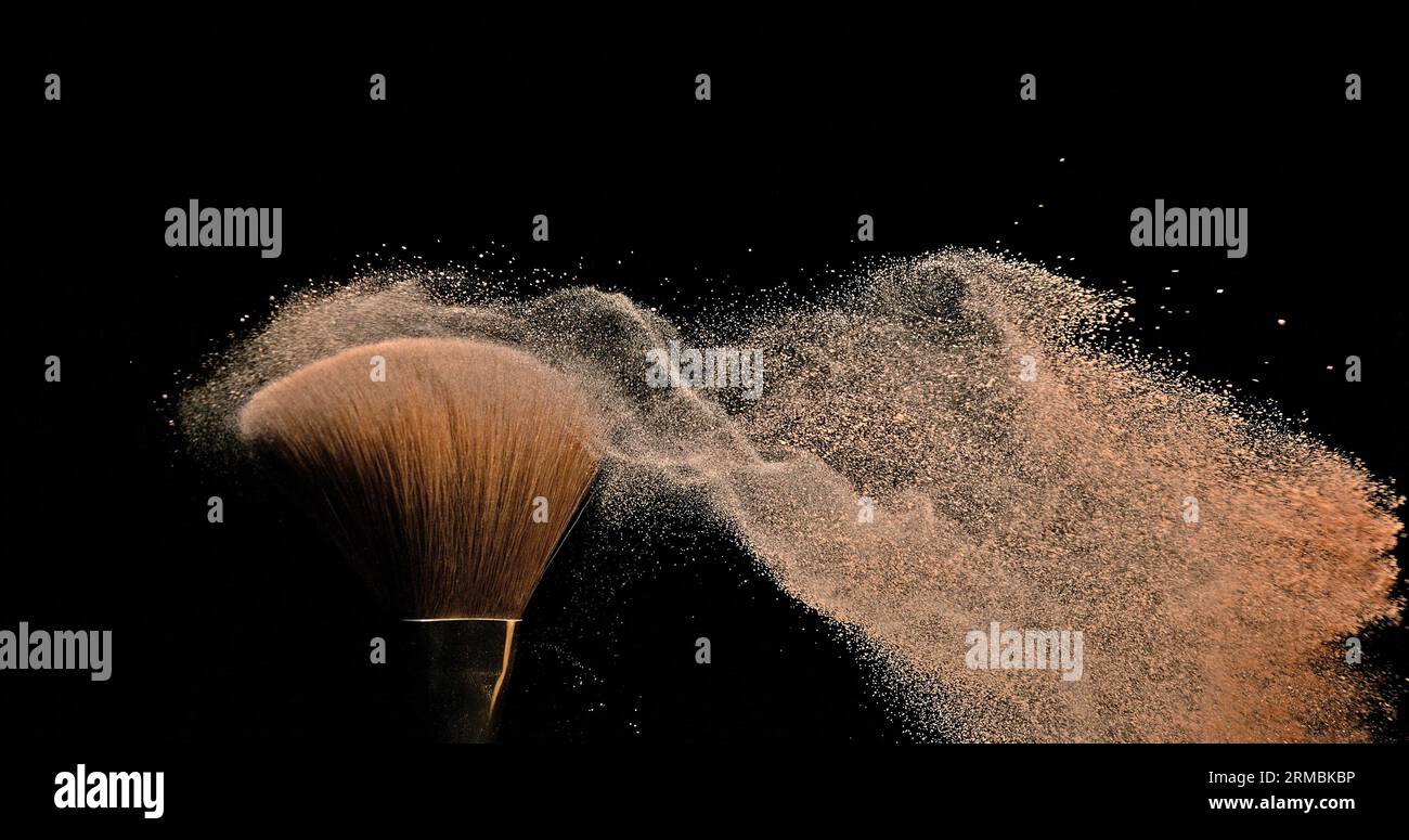 Make-up Brush spreading blush powder on black background Stock Photo ...