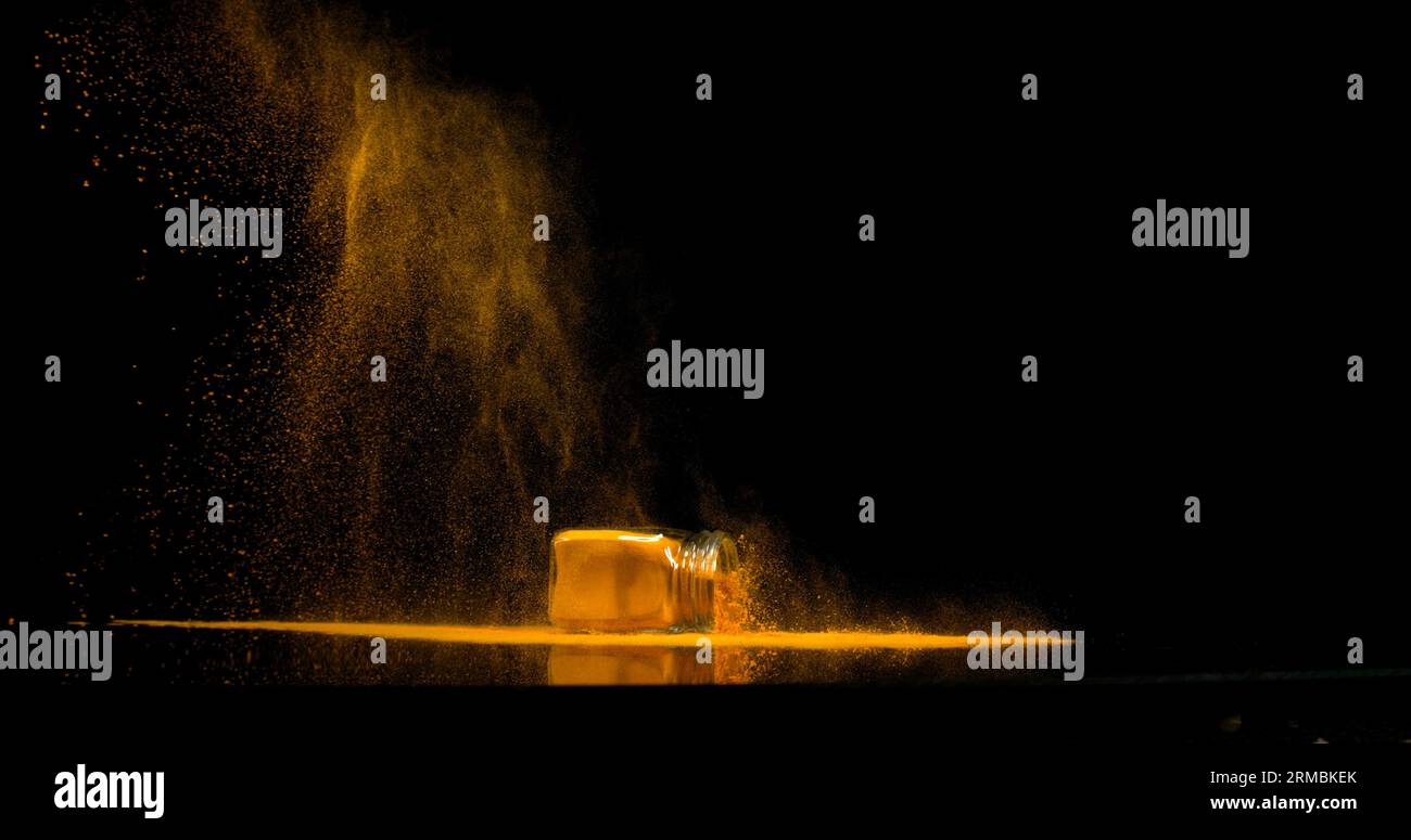 Turmeric, curcuma longa, Powder into a small jar falling against Black ...