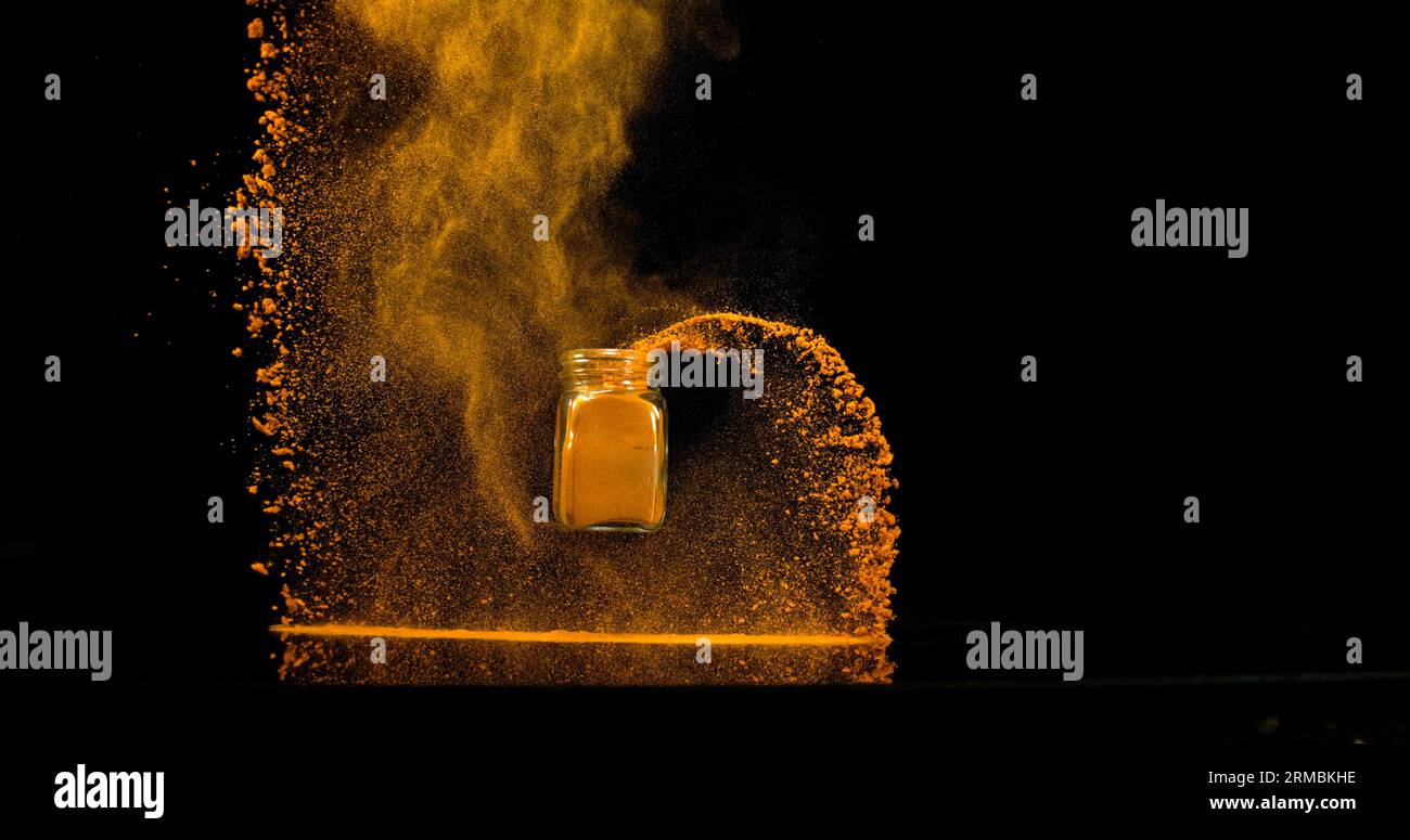Turmeric, curcuma longa, Powder into a small jar falling against Black ...