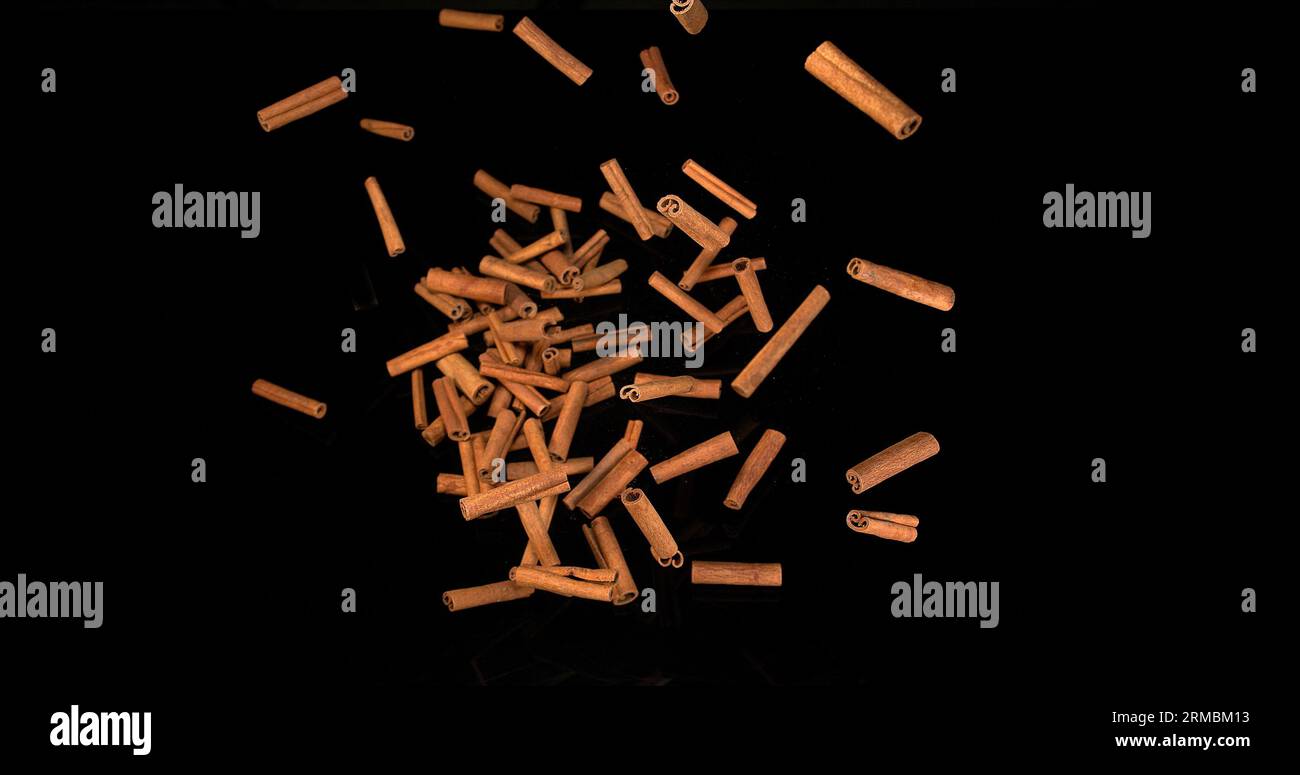 Cinnamon sticks, cinnamomum zeylanicum, spice falling against Black ...