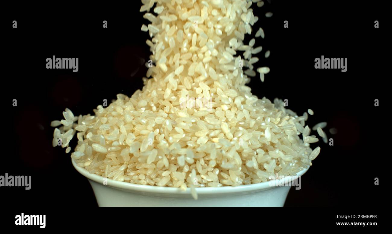 Rice falling against Black Background Stock Photo - Alamy