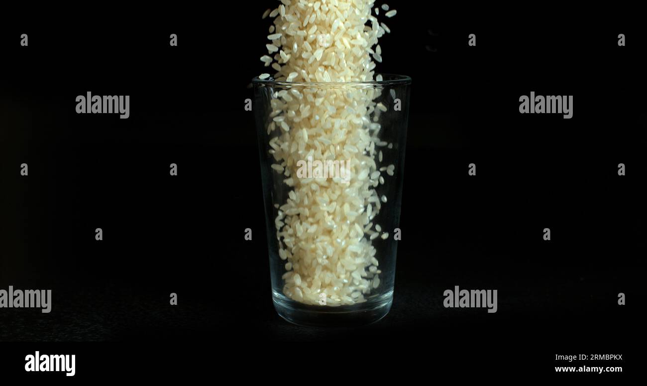 Rice falling against Black Background Stock Photo - Alamy