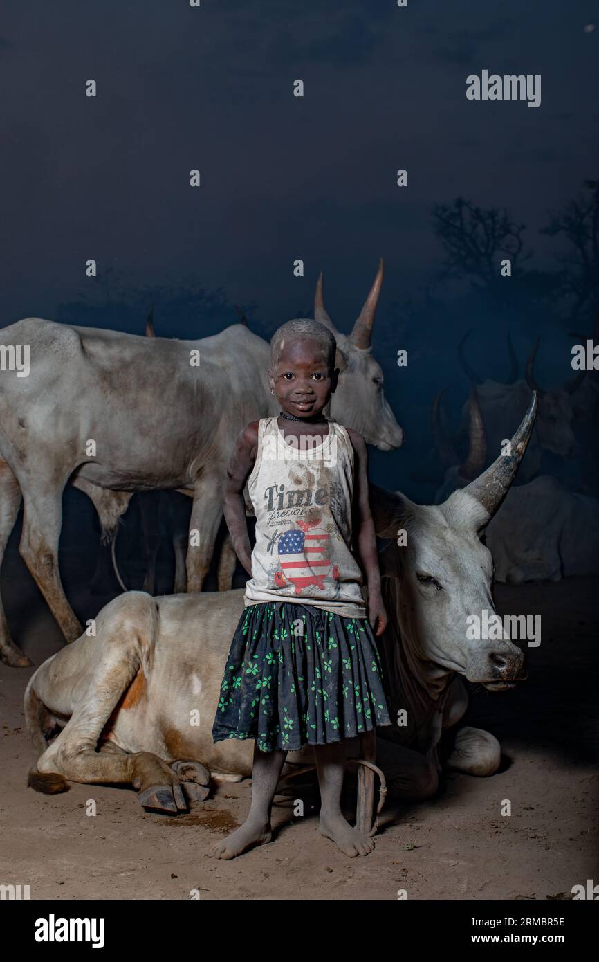 Little Mundari girl with cows in Mundari camp at night Stock Photo - Alamy