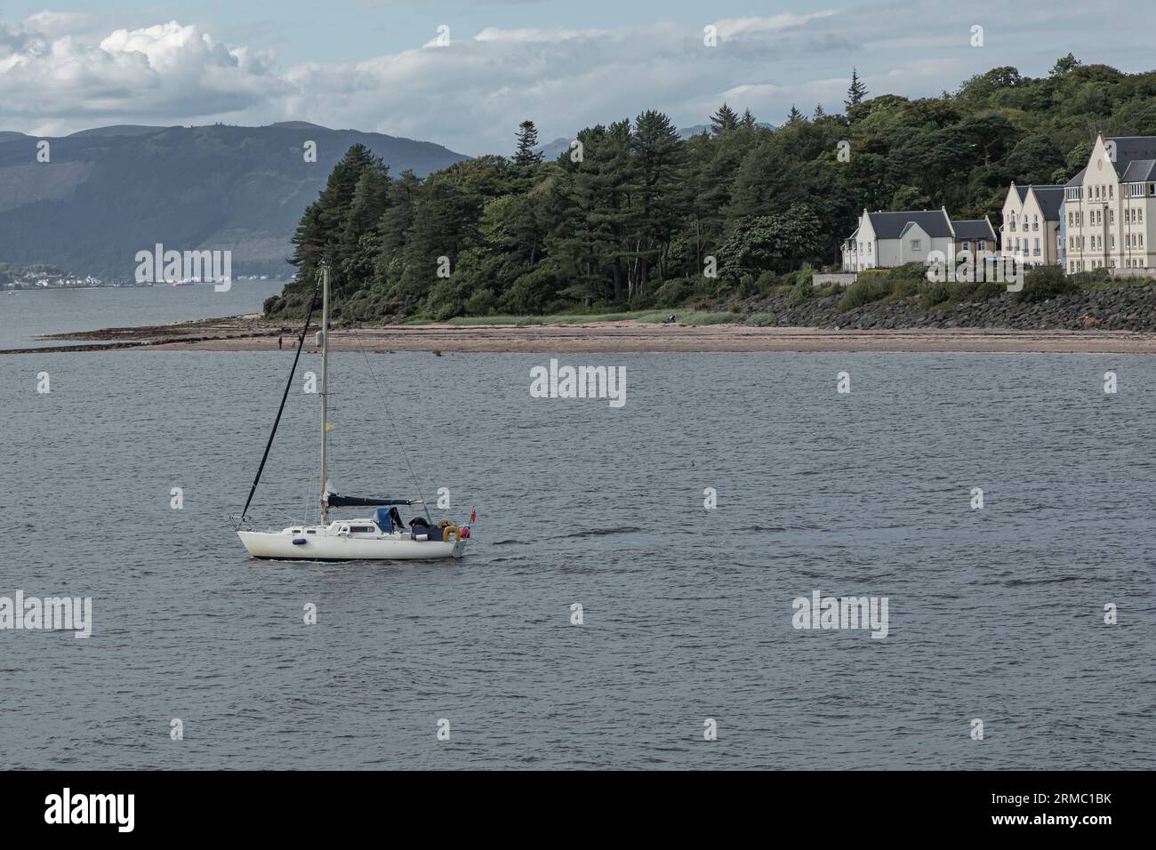 Yacht leaving the calm of the bay and crossing a sea loch on the ...