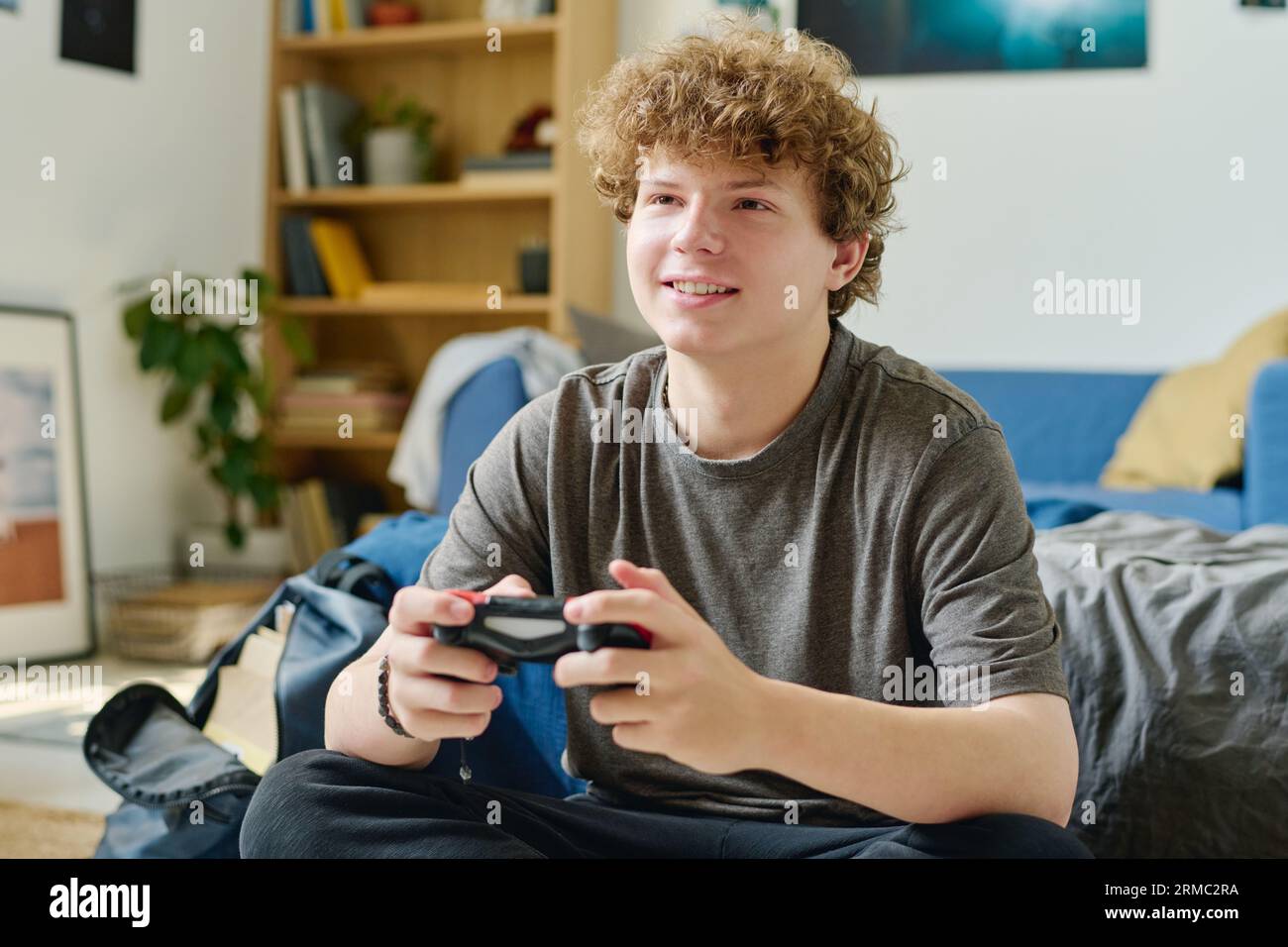 Cute smiling teenage boy with joystick pressing buttons during computer ...