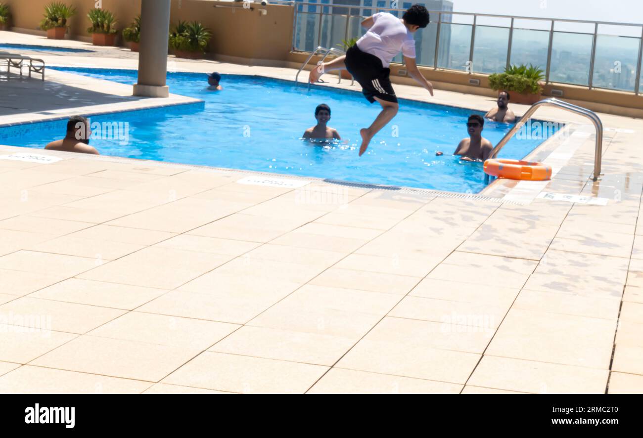 Kid jumping into water in outdoor pool. Dressed boy jumping to outdoor ...