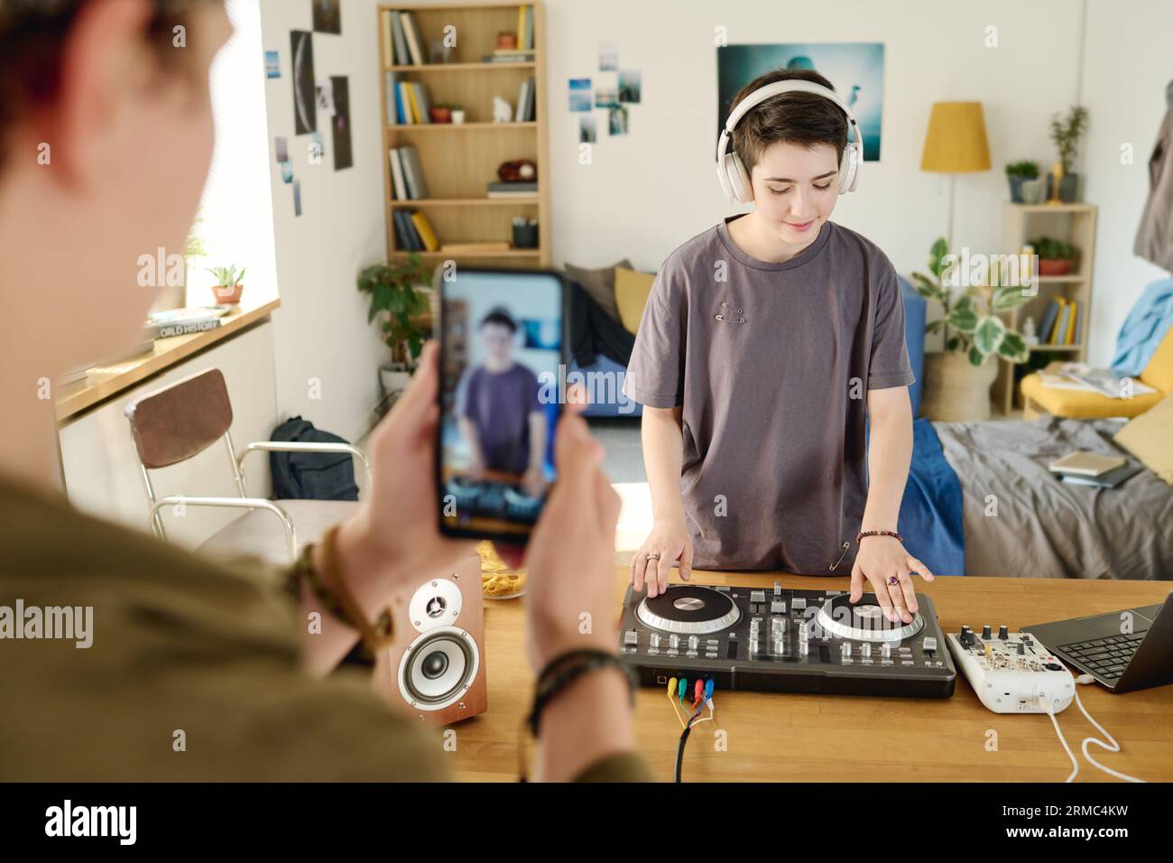 Focus on teenage girl in casualwear and headphones creating music while ...