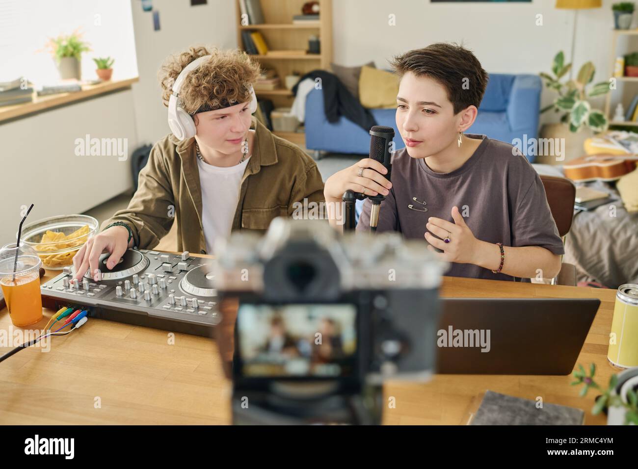 Cute brunette girl singing or speaking in microphone in front of laptop ...
