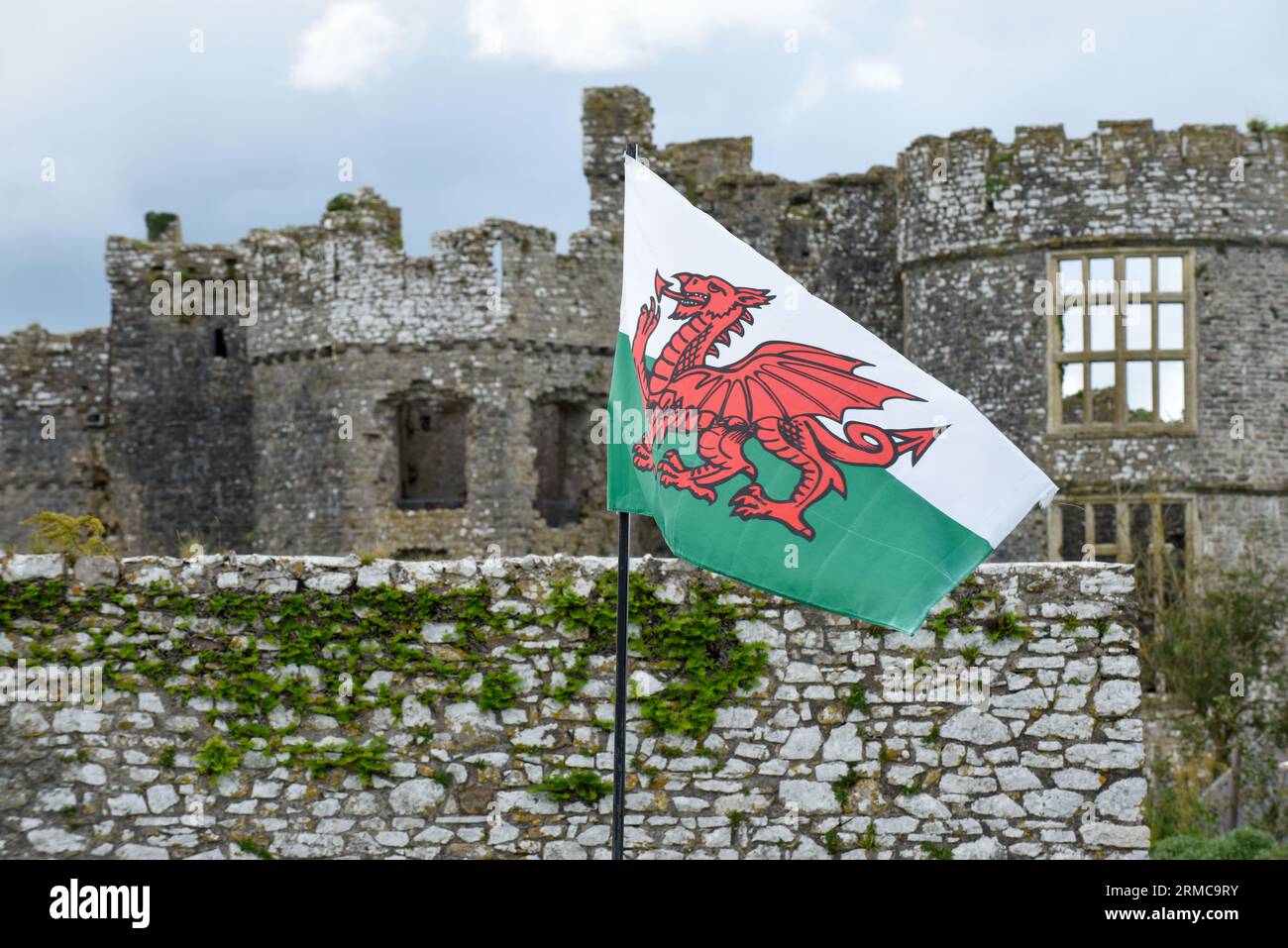 A Welsh flag with dragon symbol flying in front of an historic castle ...