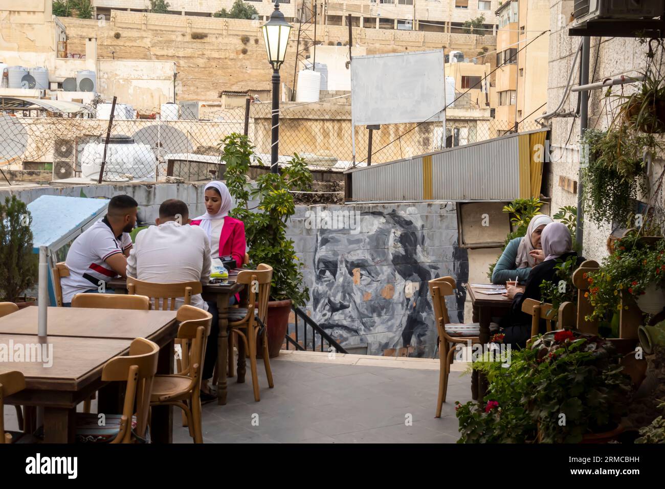 People in the cafe with street art murals in in Jabal al-Weibdeh ...