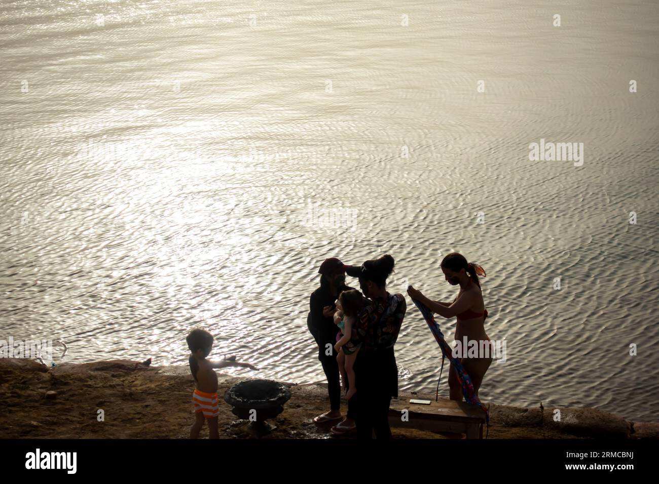 Tourists silhouettes against the setting Sun. Dead Sea, Jordan. Family ...
