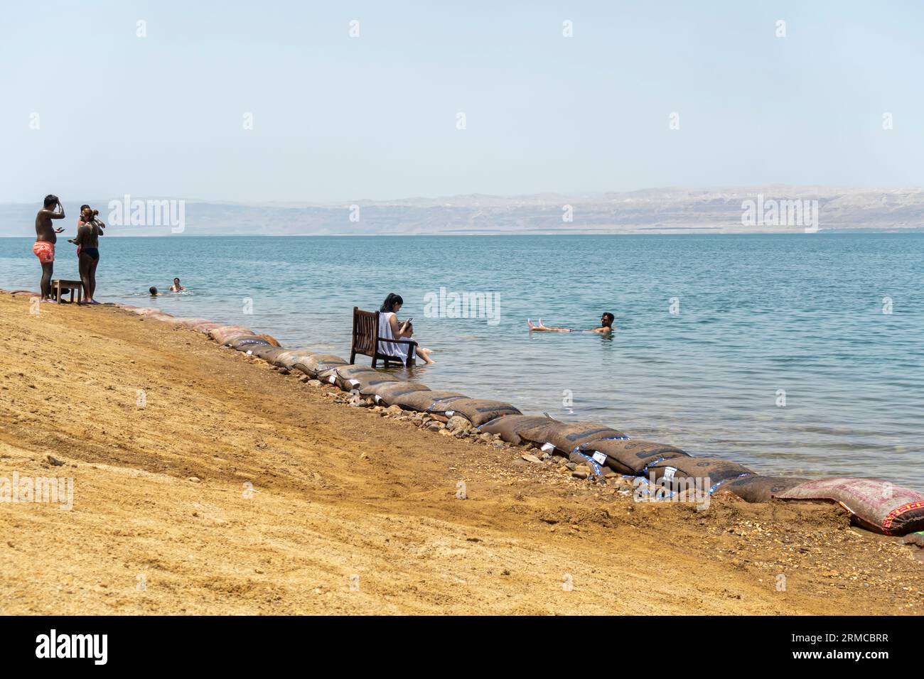 Tourists covered in mud swim in Dead Sea, Jordan Stock Photo - Alamy