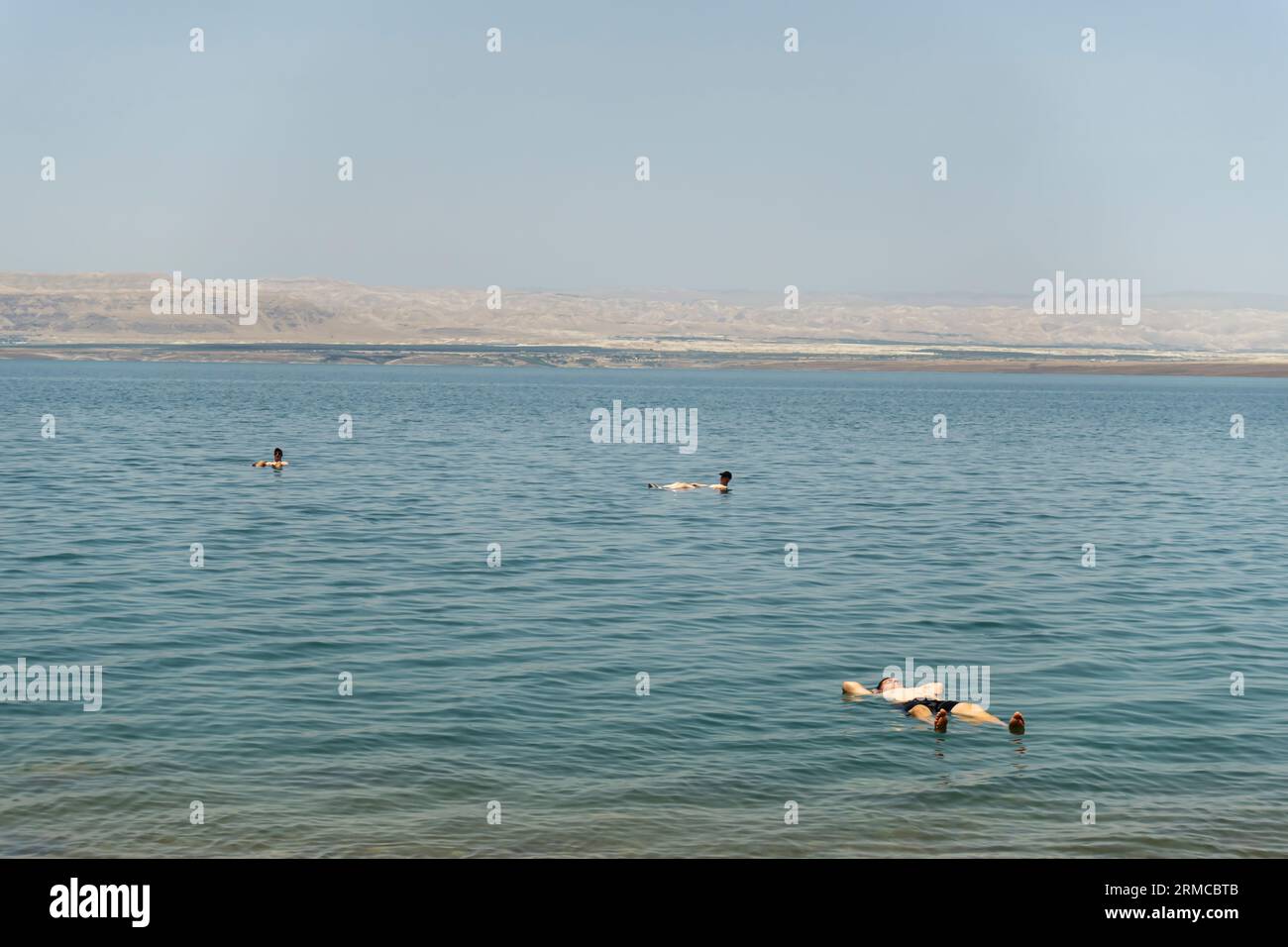 Tourists covered in mud swim in Dead Sea, Jordan Stock Photo - Alamy
