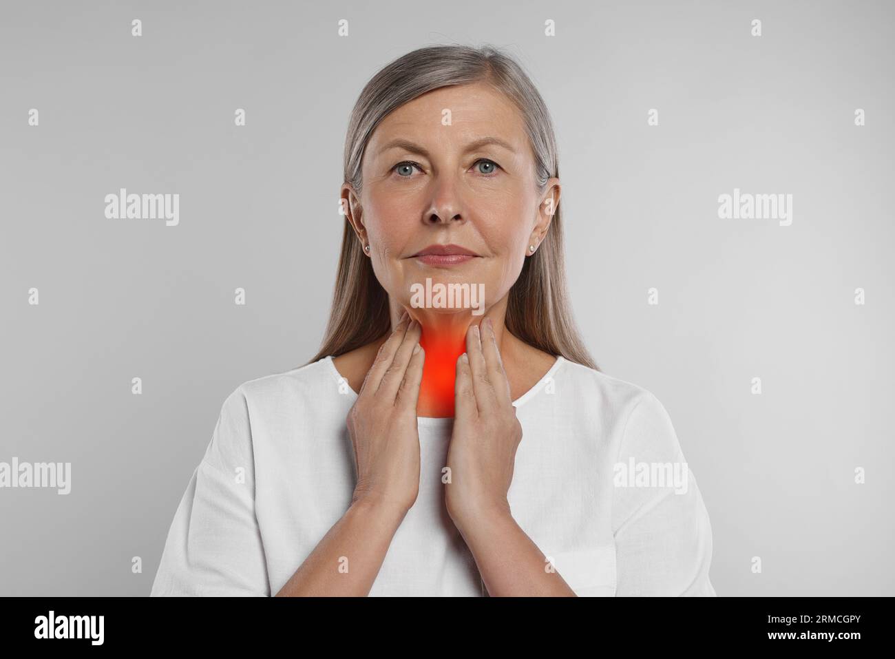 Endocrine system. Senior woman doing thyroid self examination on light ...