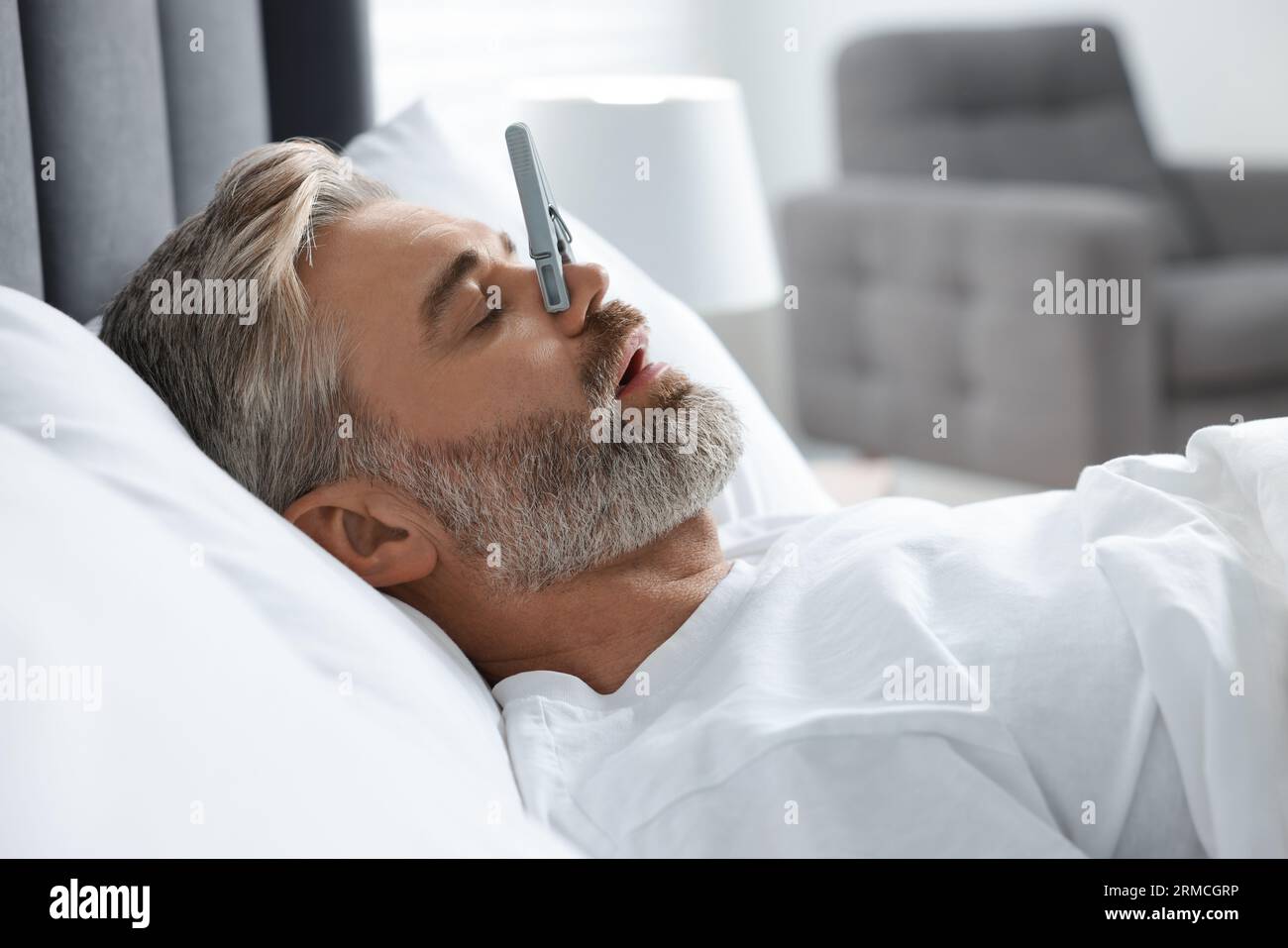 Man sleeping with clothespin on his nose in bed at home. Problem with ...