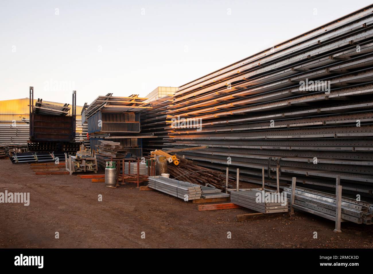 Neatly arranged stacks of heavy metal materials fill a work yard ...