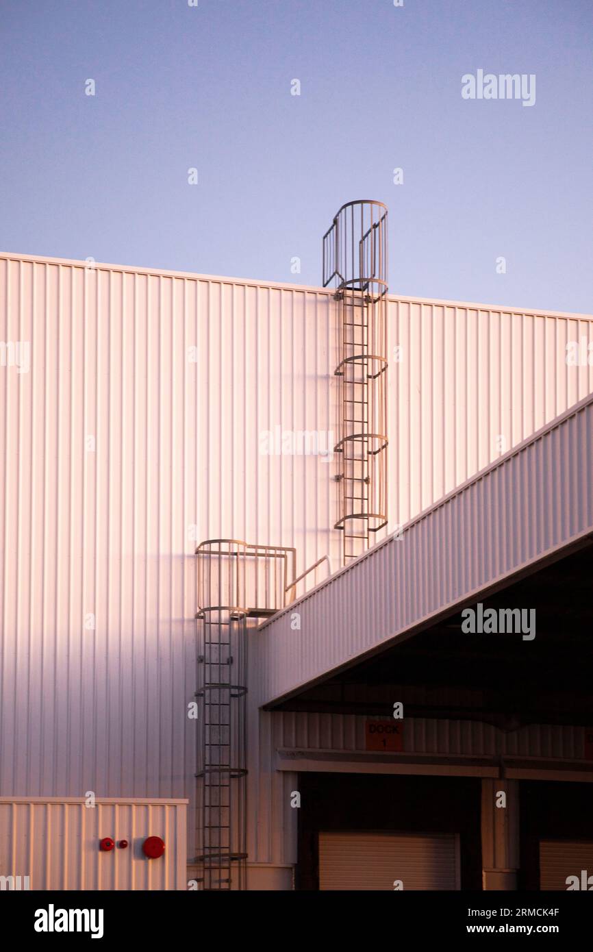 Stationary steel ladder offers vertical access a white warehouse wall ...