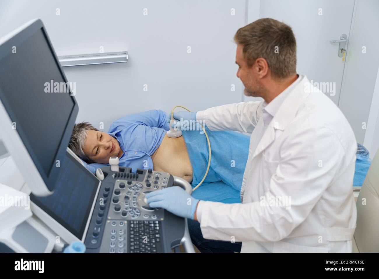 Male sonographer doing abdominal ultrasound scanning for patient in ...