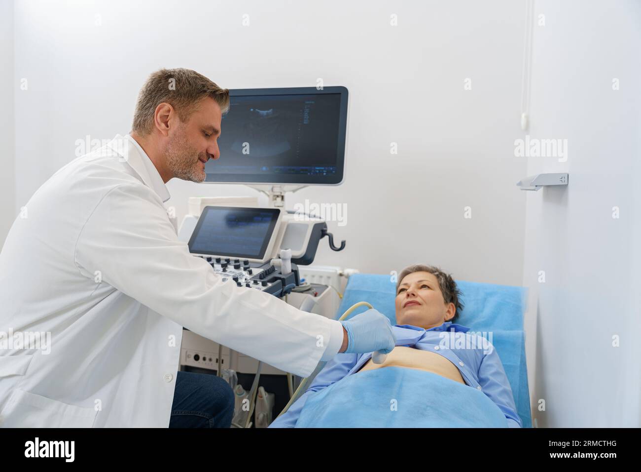 Male sonographer doing abdominal ultrasound scanning for patient in ...