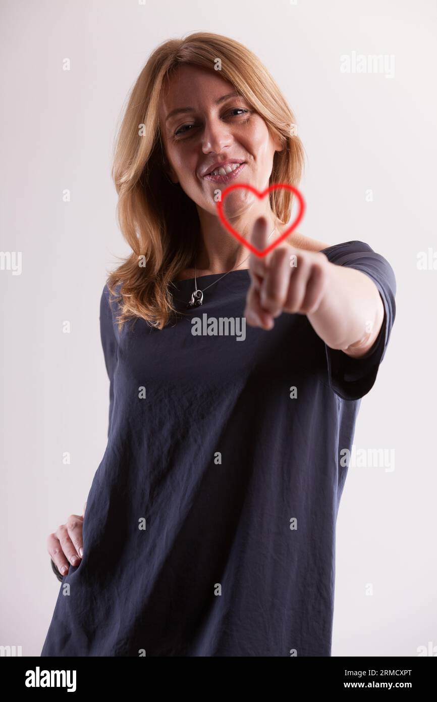 radiant blonde woman around 40, with fair skin, joyfully touches a ...