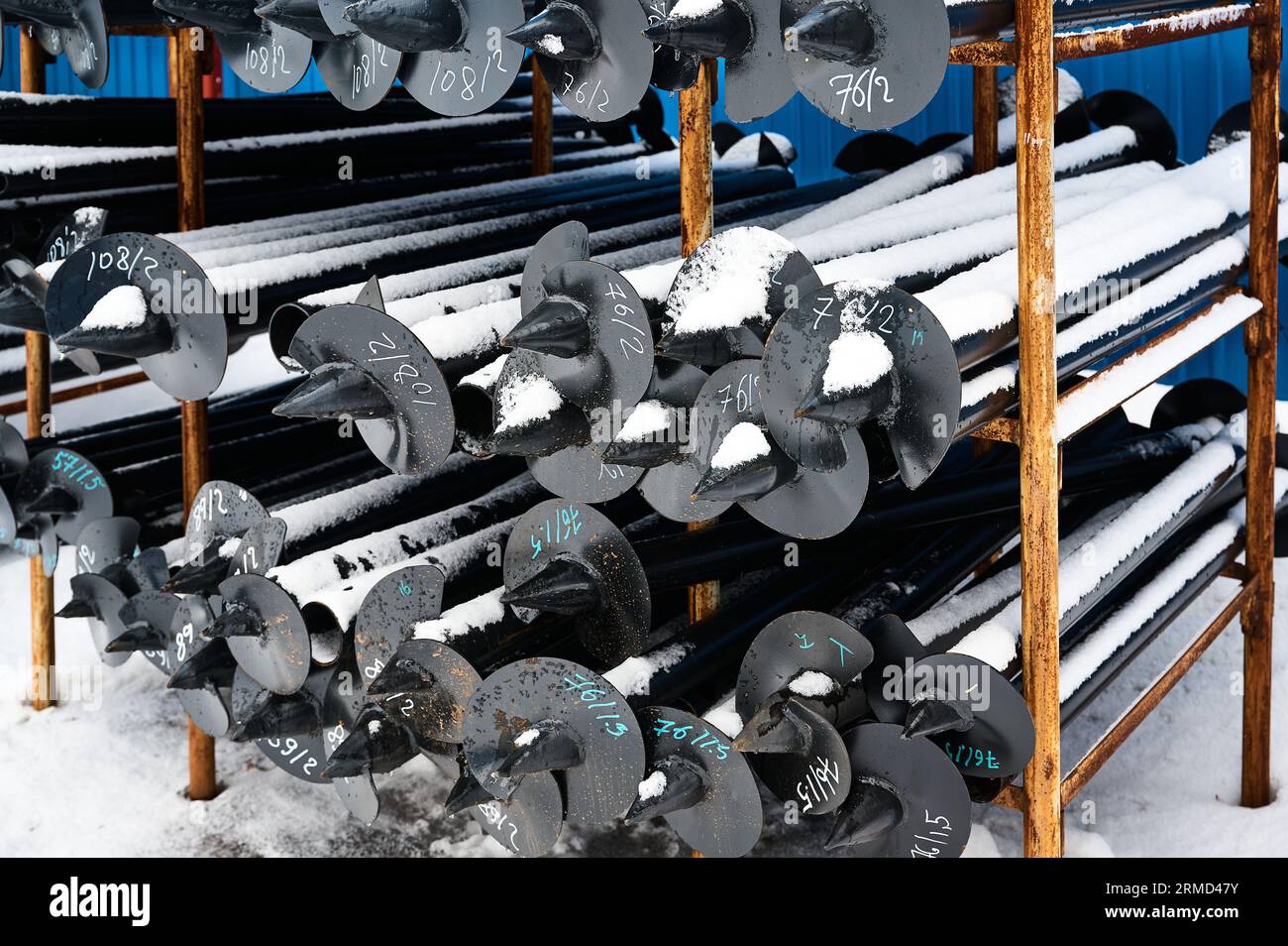 Helical piles on rusty metal rack in snowy warehouse yard Stock Photo ...